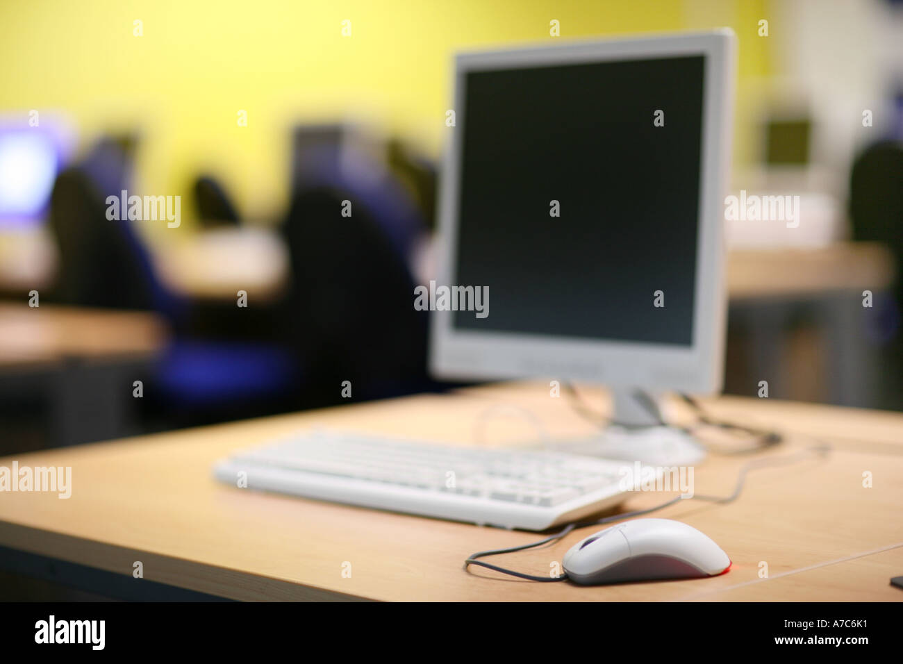 Flat computer monitor screen and mouse in large open plan office ...