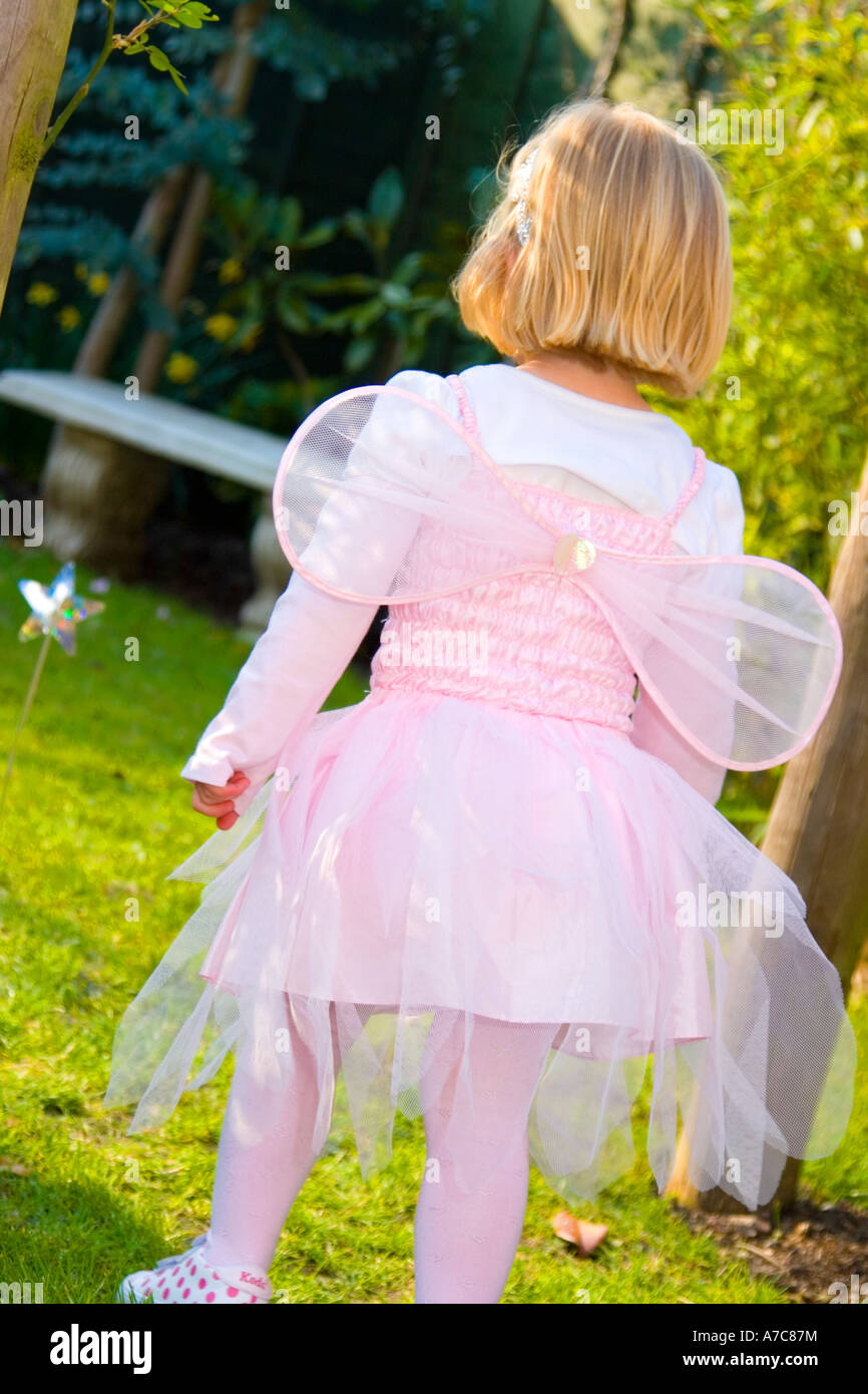 Young girl dressed as fairy, running in summer garden with back to ...