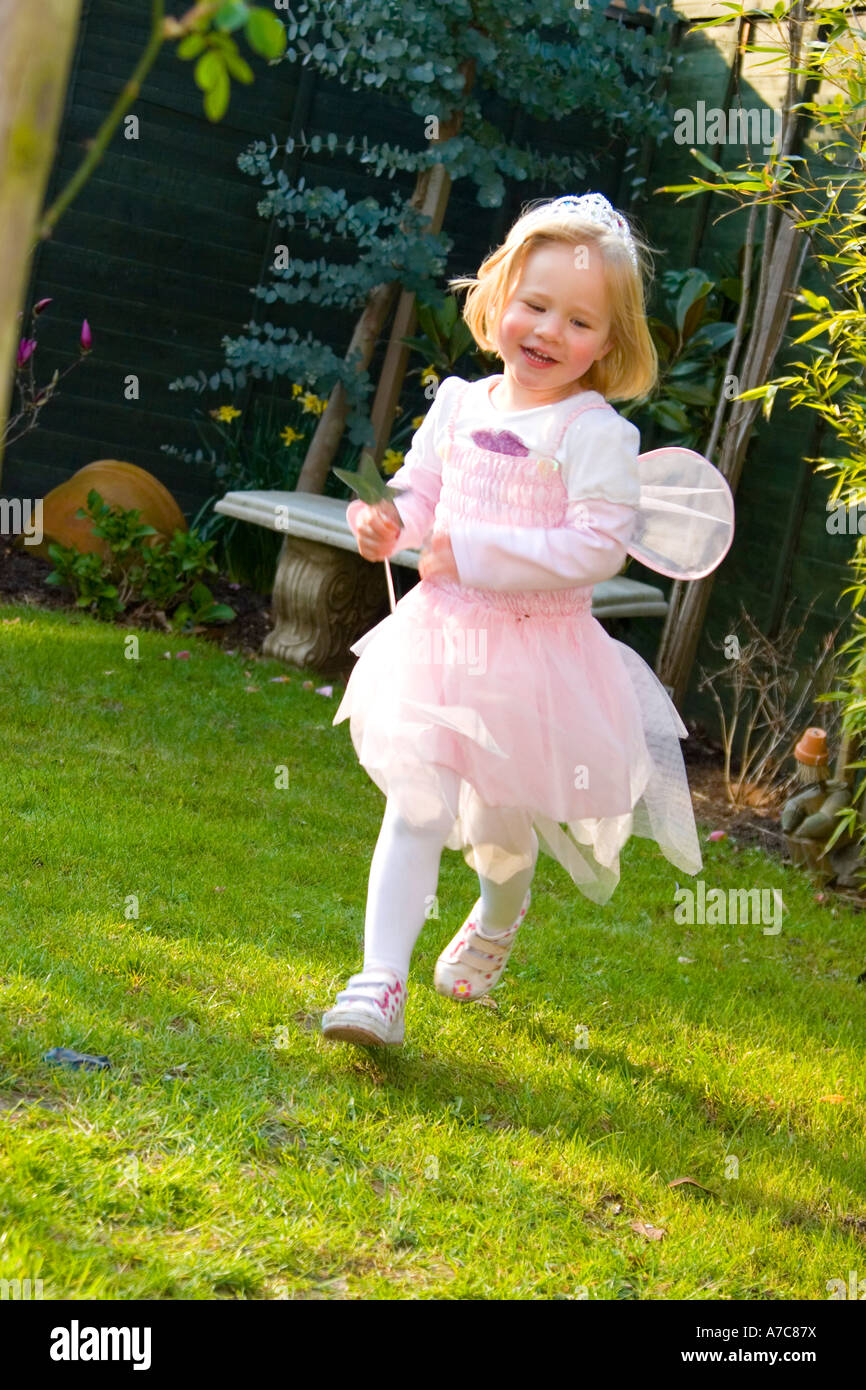 Young girl dressed as fairy, running in summer garden towards camera ...