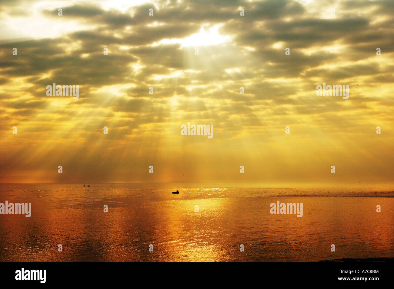 Graphic deep golden sunrise with sunlight filtering through gold clouds ...