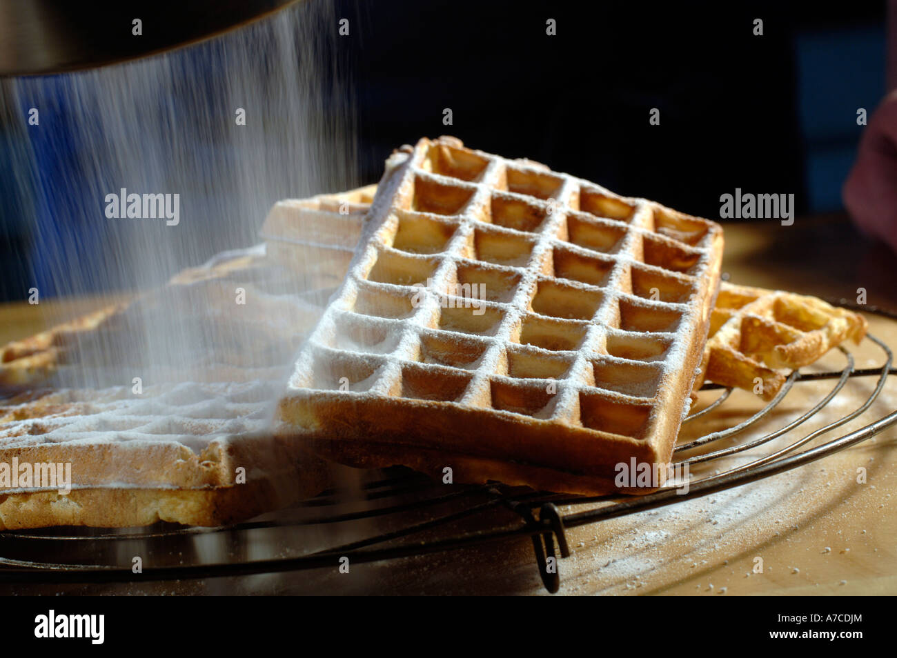 Making waffles dusting them with icing sugar when cooked Stock Photo ...