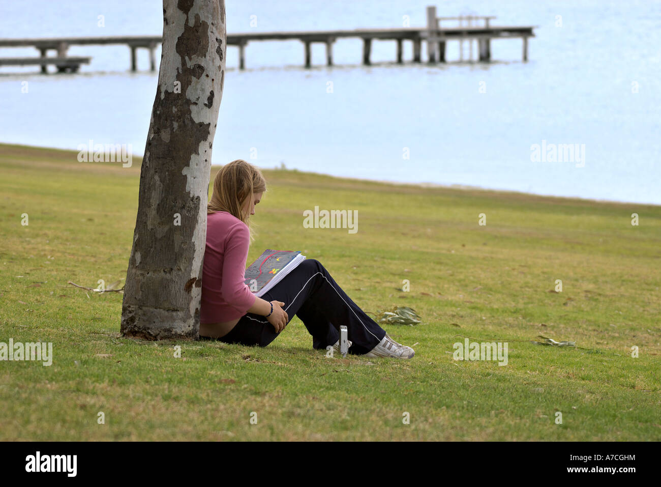 Girl leaning against tree reading hi-res stock photography and images ...