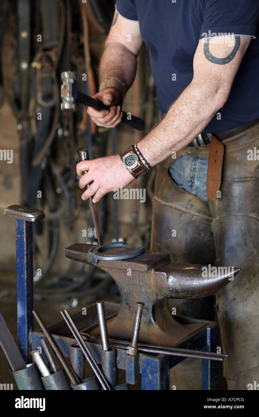 Blacksmith working with old fashioned traditional tools on horse shoes ...