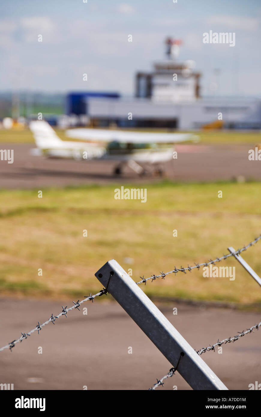Security fence with Airport Terminal Building and light aircraft out of ...