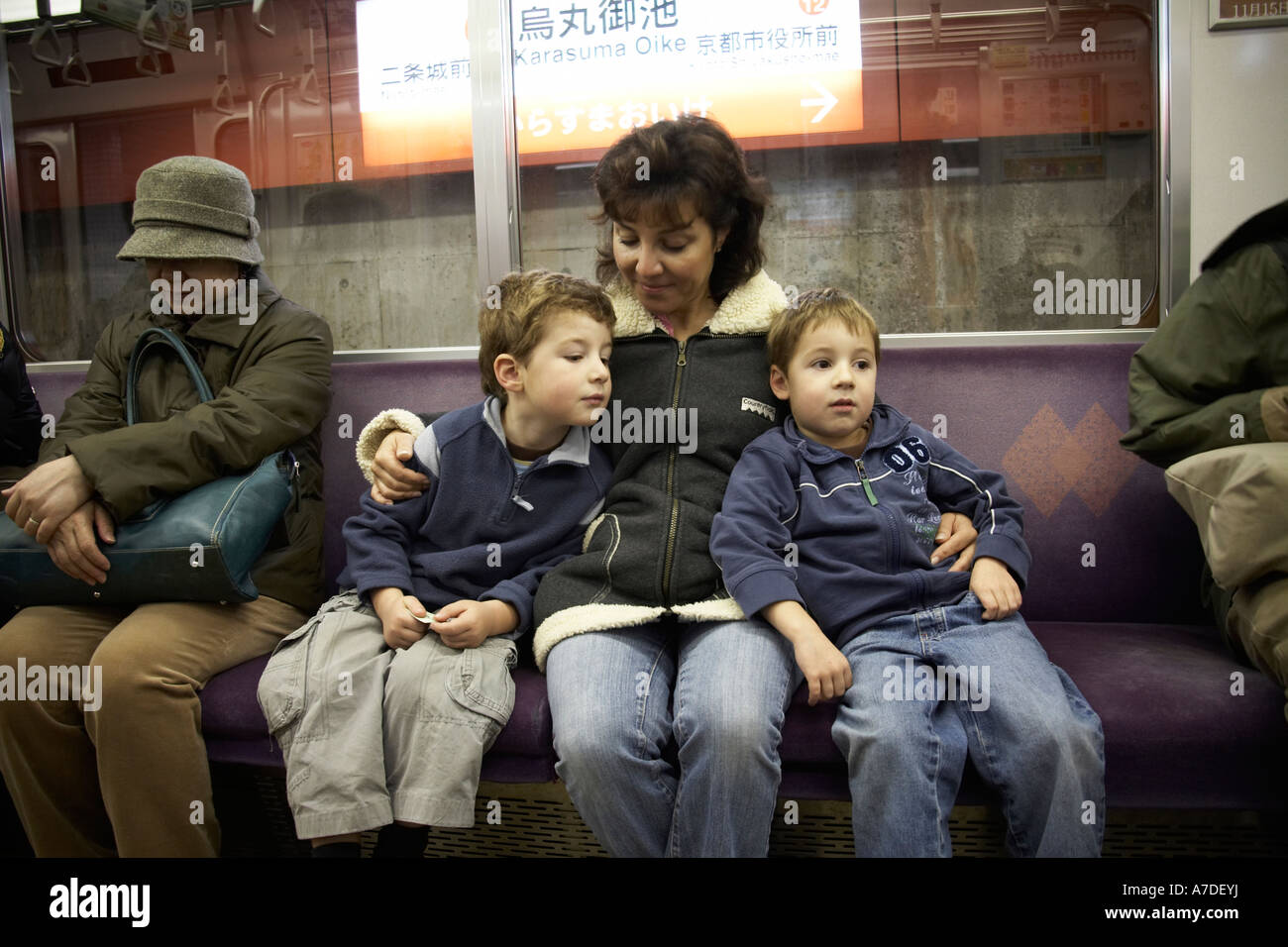 Western woman mother and two boy sons sitting travelling on Subway ...