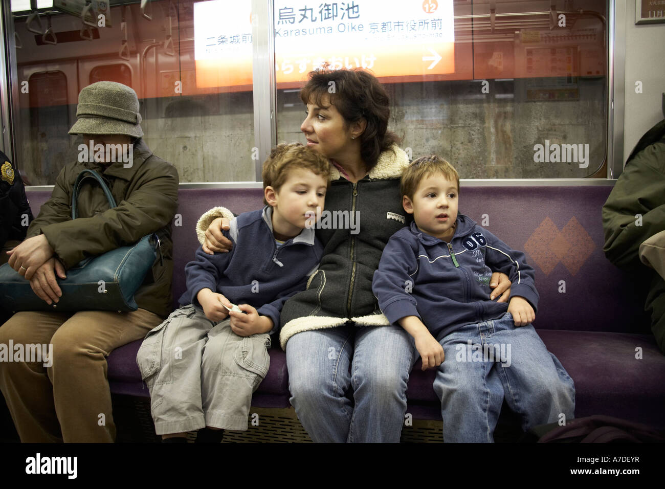 Western woman mother and two boy sons sitting travelling on Subway ...