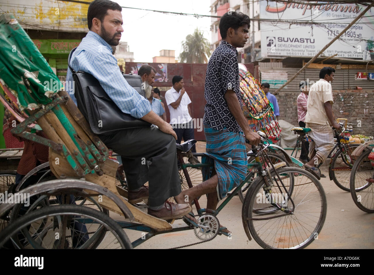 A rickshaw puller and passenger riding in the streets of Dhaka ...