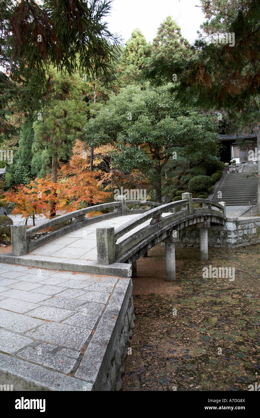 Stone bridge over pool or pond with Red and gold autumn maple tree ...
