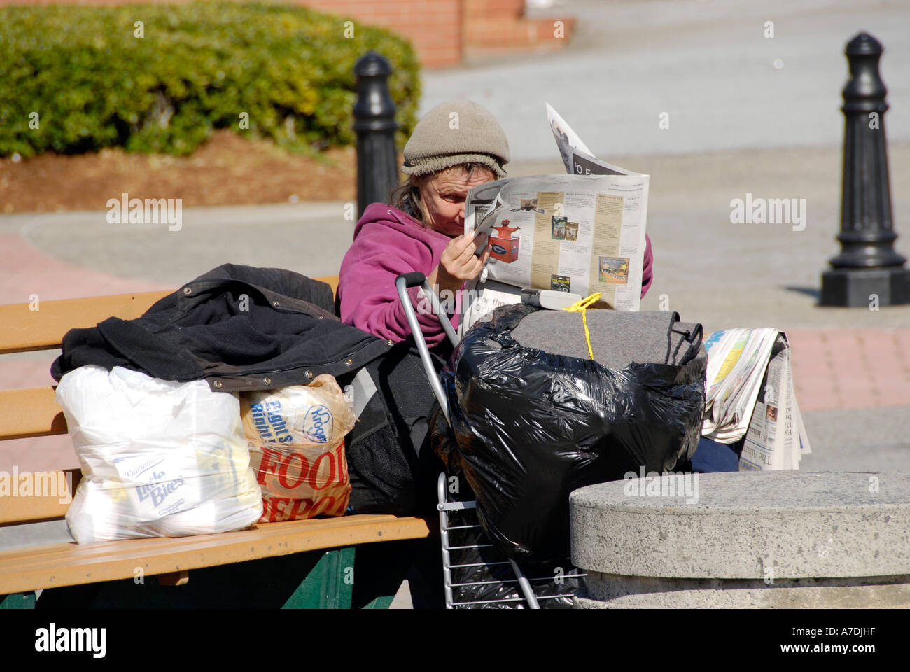 Homeless woman reads the newspaper on a bench in the Atlanta Georgia ...