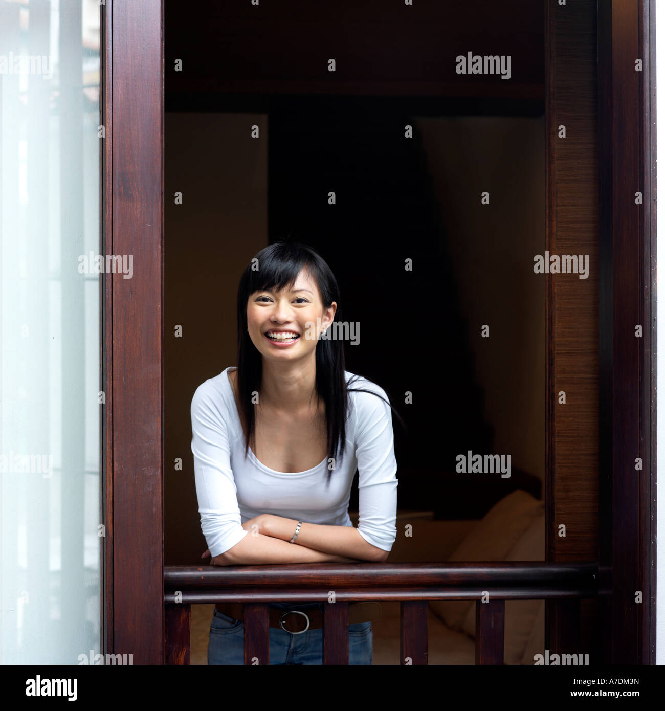 A Happy woman standing leaning forward against a wooden hand rail Stock ...