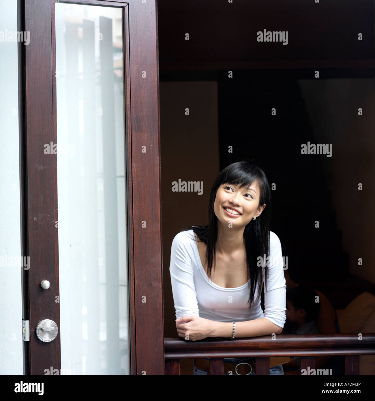 A Happy woman standing leaning forward against a wooden hand rail Stock ...