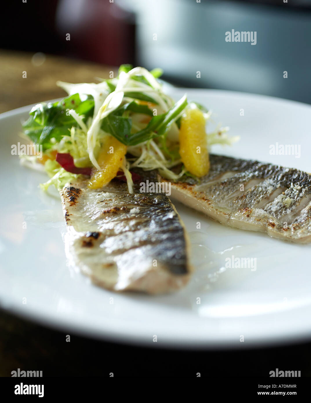 Sea bass on a plate with a salad Stock Photo - Alamy