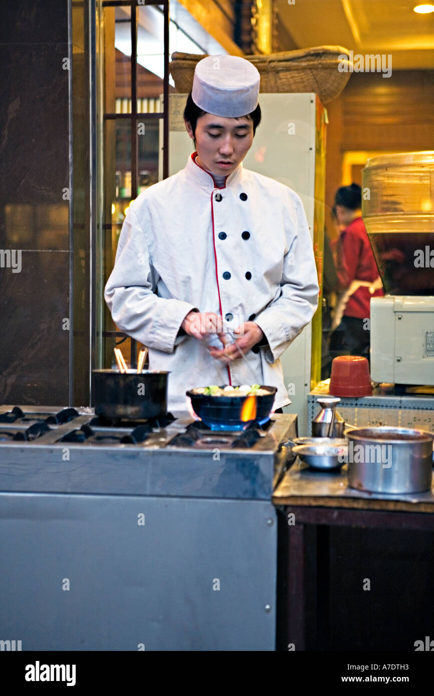 CHINA XI'AN Young restaurant worker cooking at sidewalk stand outside ...