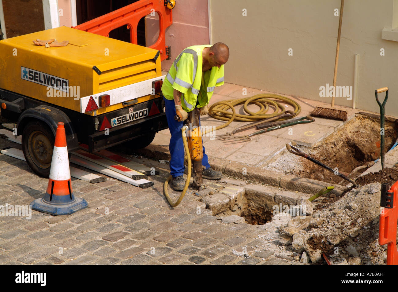 Roadworks Workman uses a pneumatic drill to dig a hole in the road ...