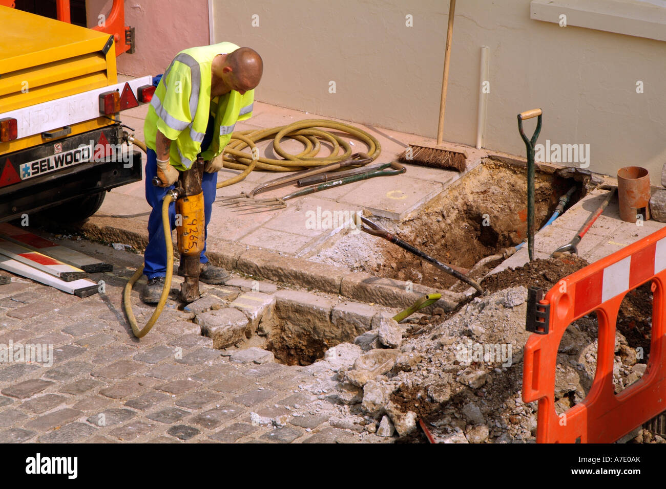 Roadworks Workman uses a pneumatic drill to dig a hole in the road ...