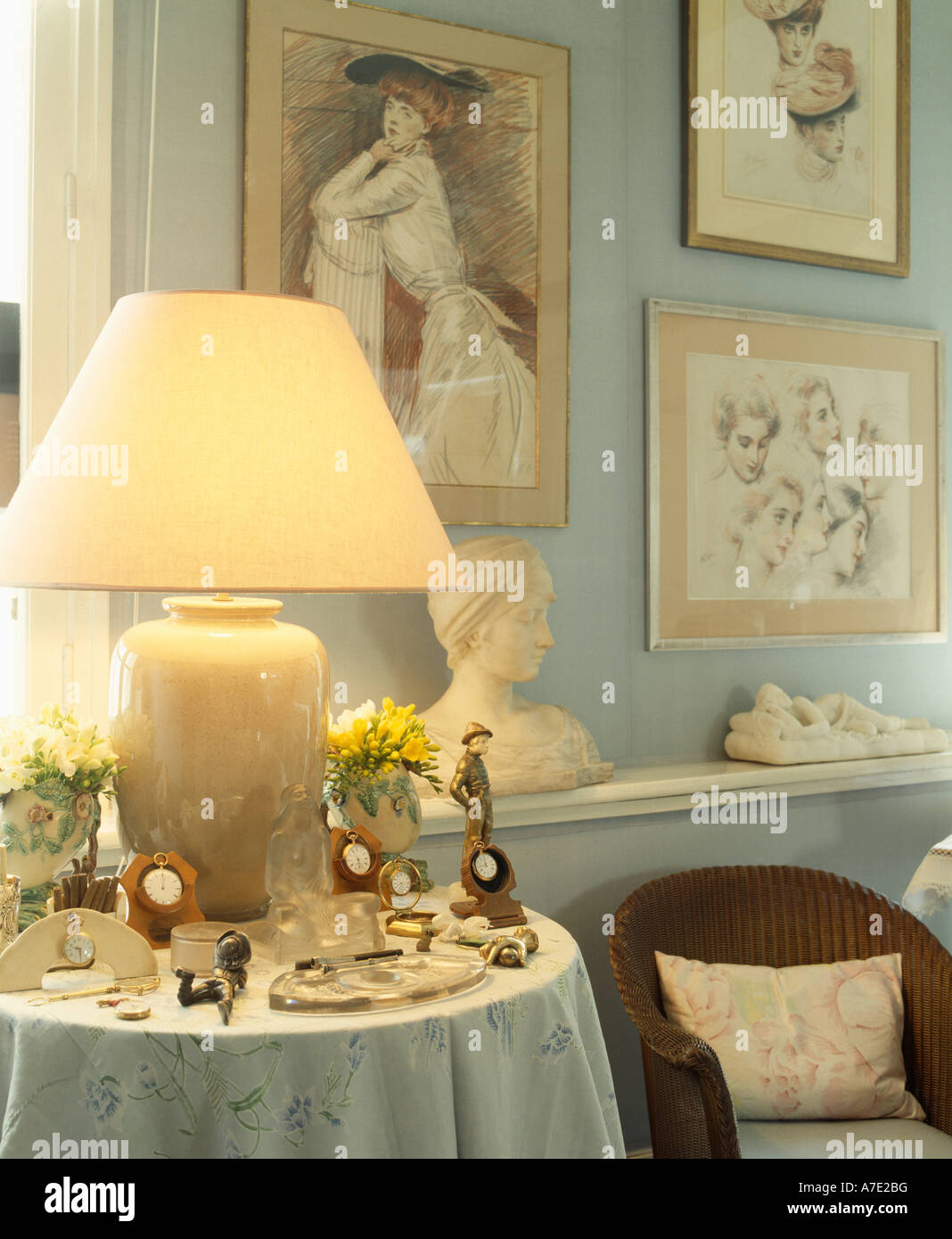 Lighted lamp with white ceramic base on small circular table with clock ...