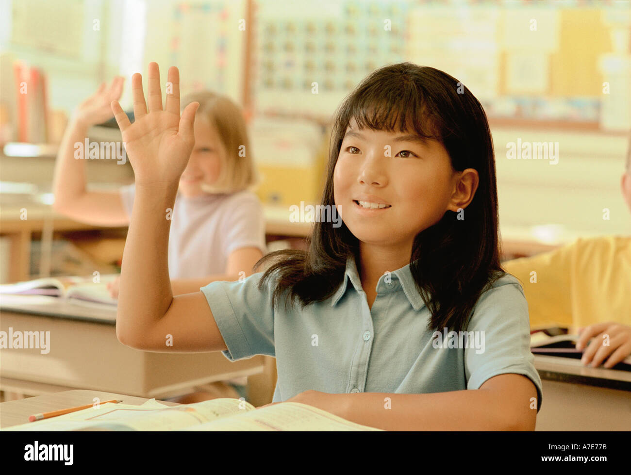 Eager girl raising hand in class Stock Photo - Alamy