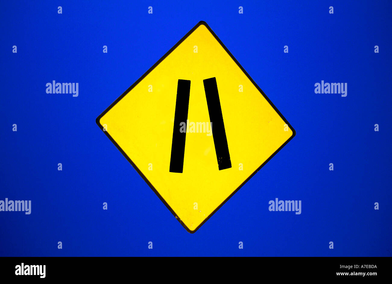 Yellow road sign with road narrows symbol on blue background Landscape ...