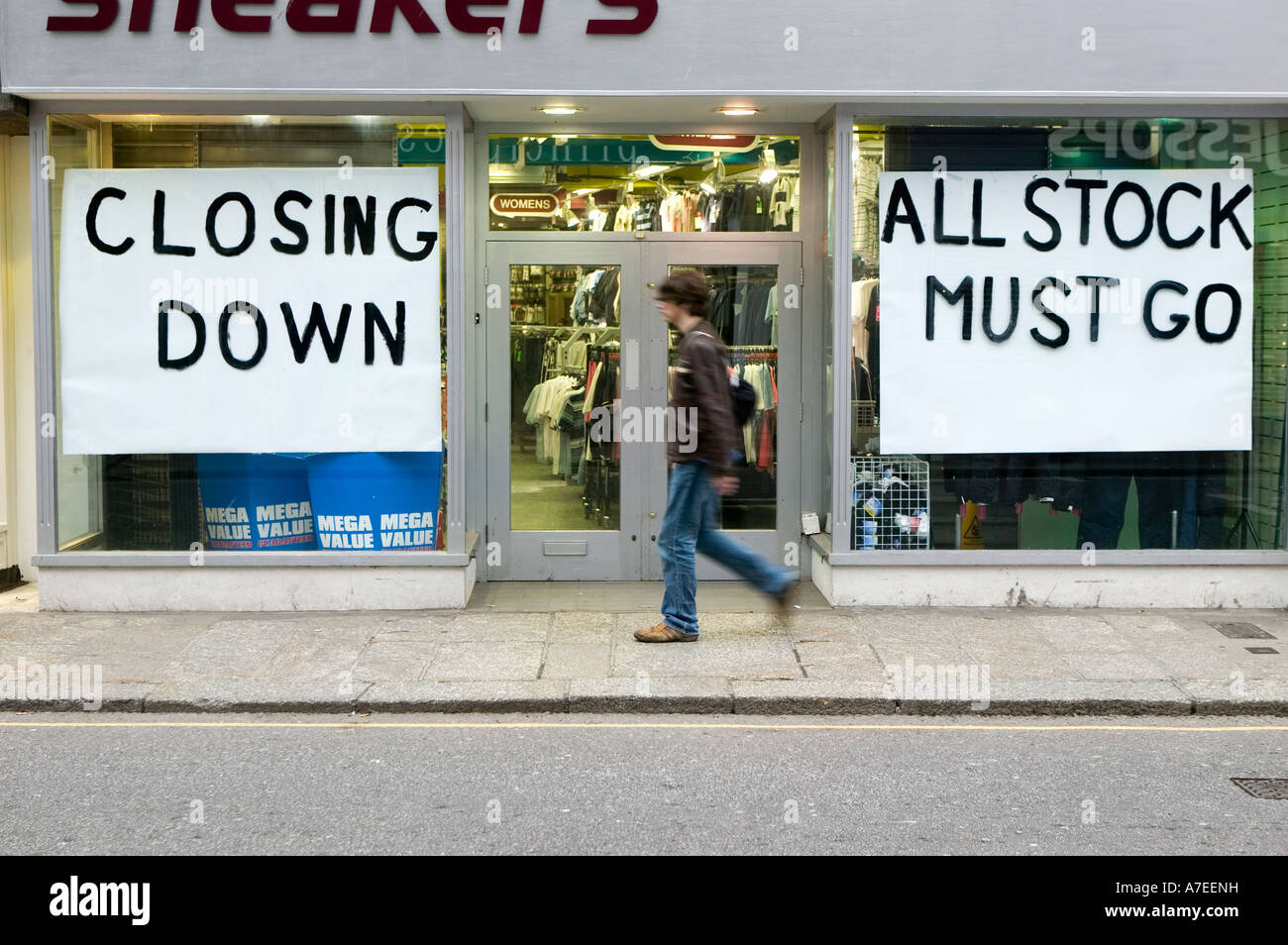 A man walks past a shop displaying closing down signs Stock Photo - Alamy