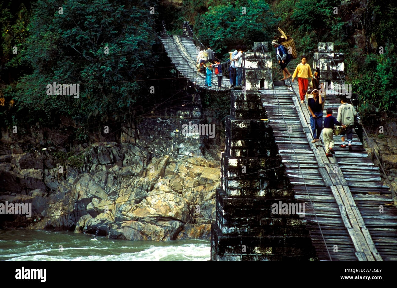 People walking across a suspension bridge over the Salween river in ...