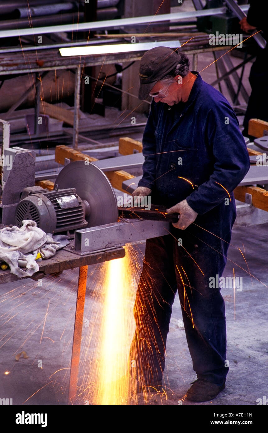Man wearing protective clothing using a grinding machine with lots of ...