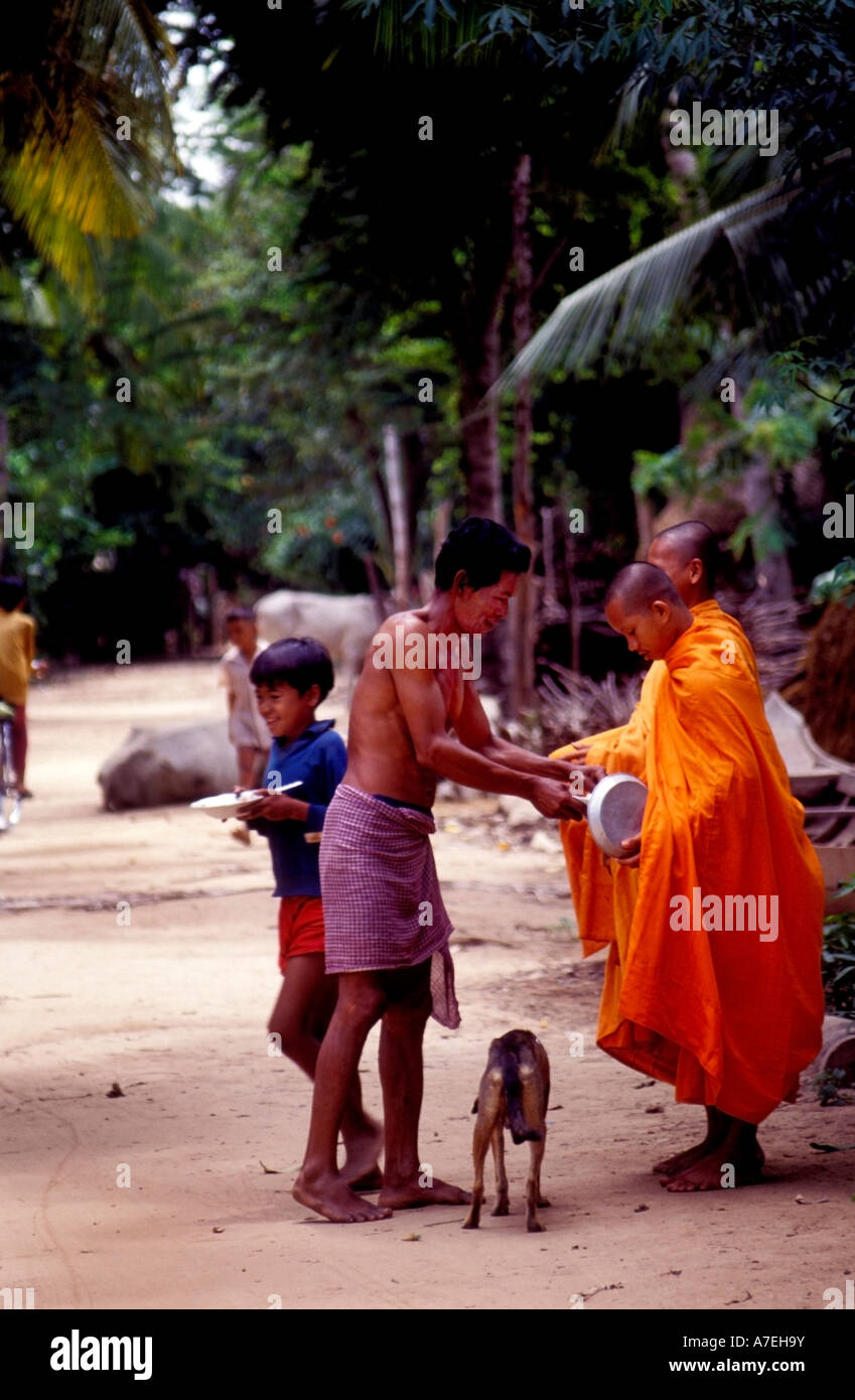 Man and boy giving alms to Buddhist monk Stock Photo - Alamy
