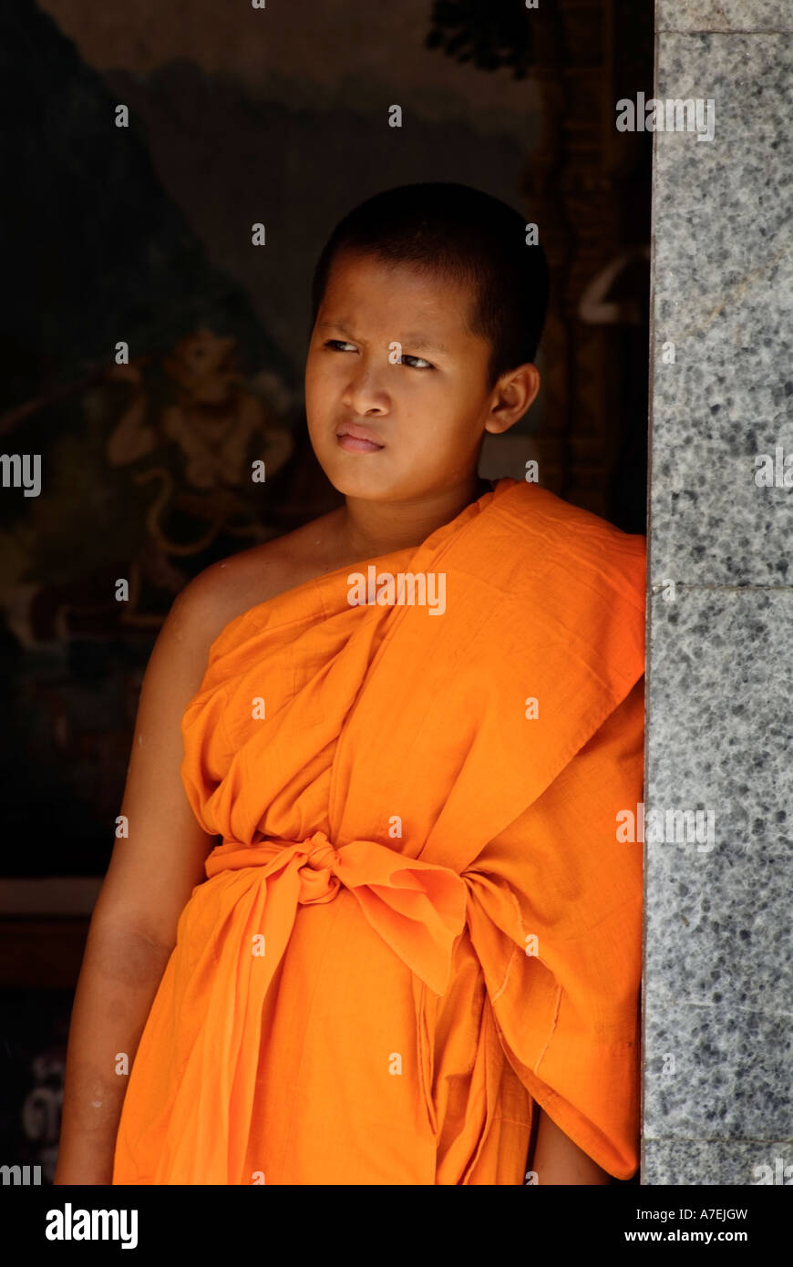 Young novice monk wearing orange leaning against a pillar Stock Photo ...