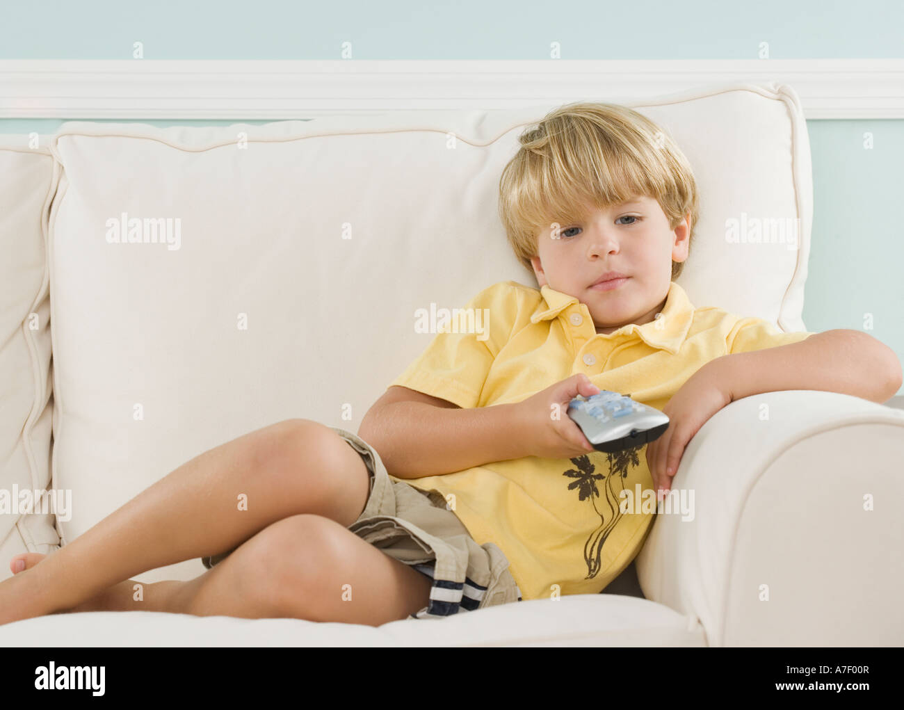 Young boy on sofa pointing remote control Stock Photo - Alamy