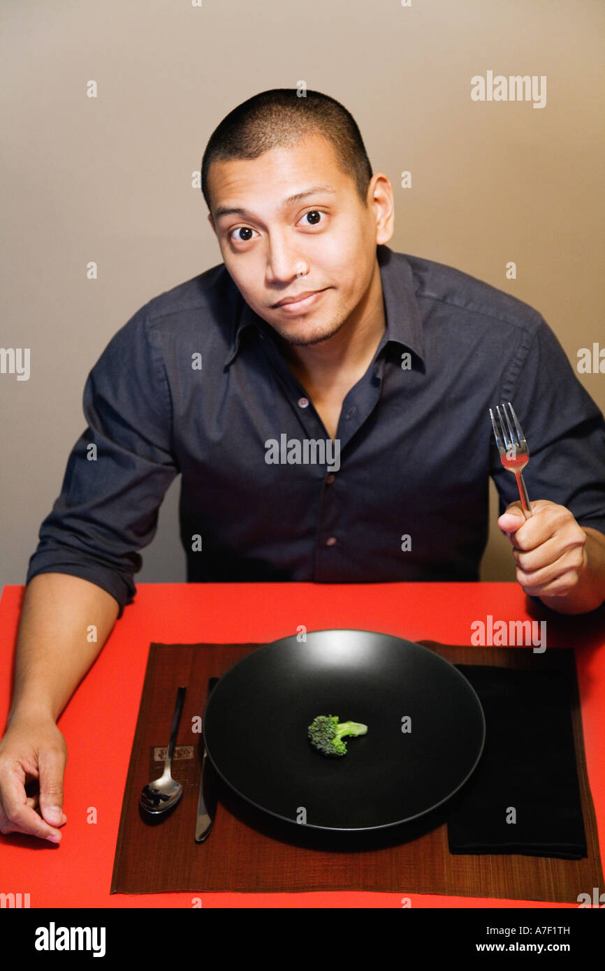 Asian man with one piece of broccoli on plate Stock Photo - Alamy