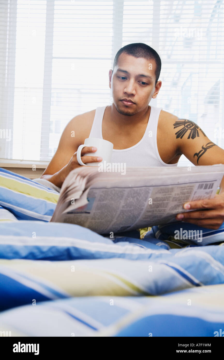 Asian man reading newspaper in bed Stock Photo - Alamy