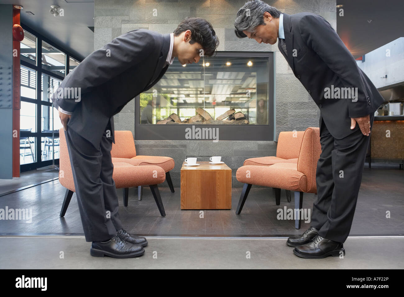 Two businessmen bowing to each other in cafe Stock Photo - Alamy