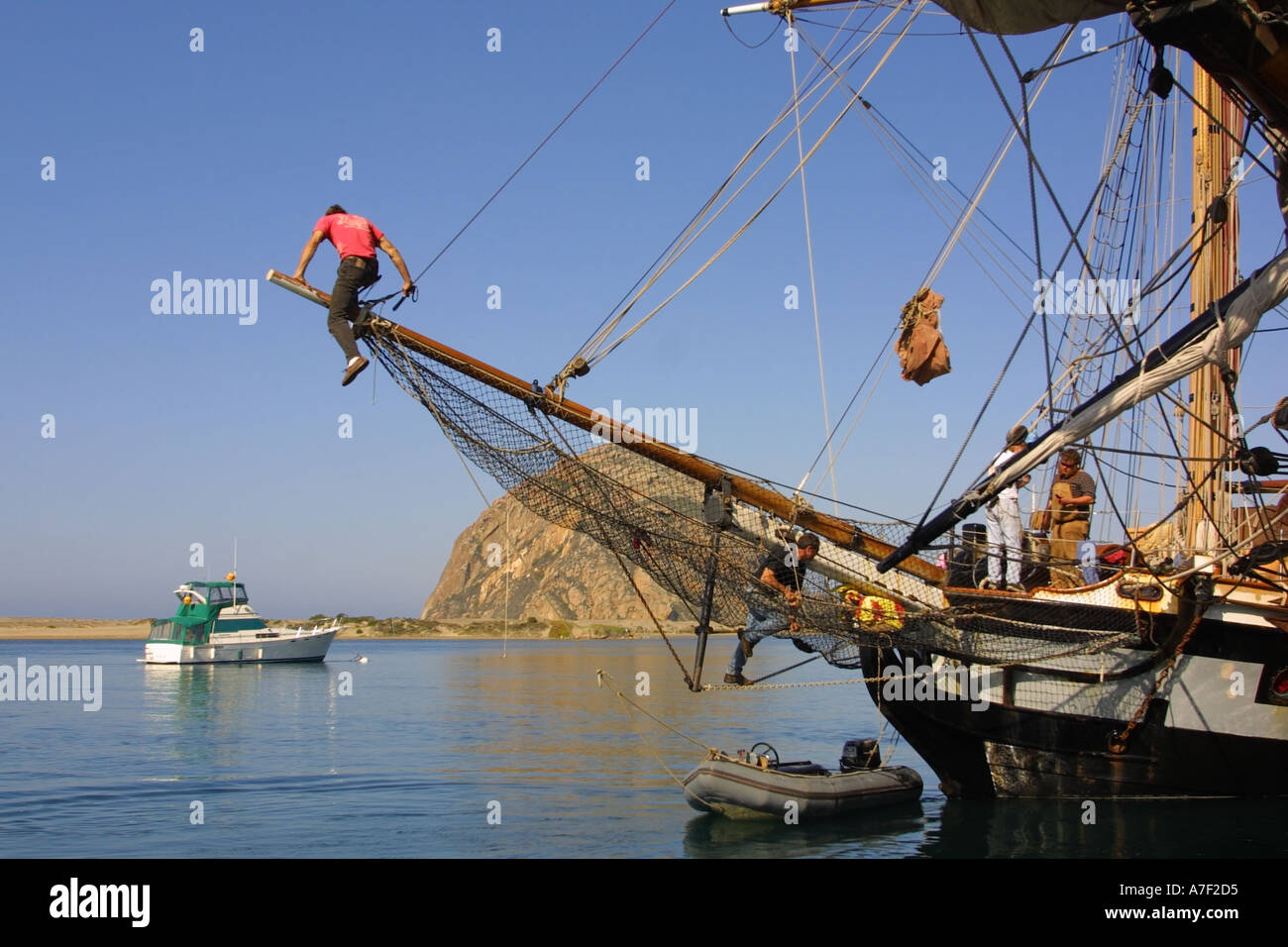 Crewman scrapes paint on bowsprit of Hawaiian Chieftan sailing ketch ...