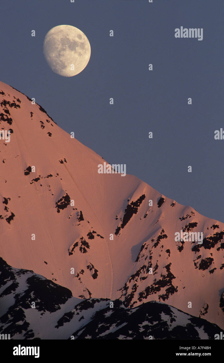 USA Alaska Gibbous moon rises above snow covered Kenai Range peaks ...