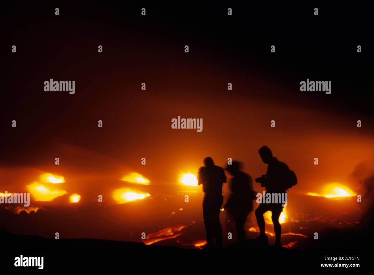 USA Hawaii Volcanoes National Park Tourists lit by flames as lava burns ...