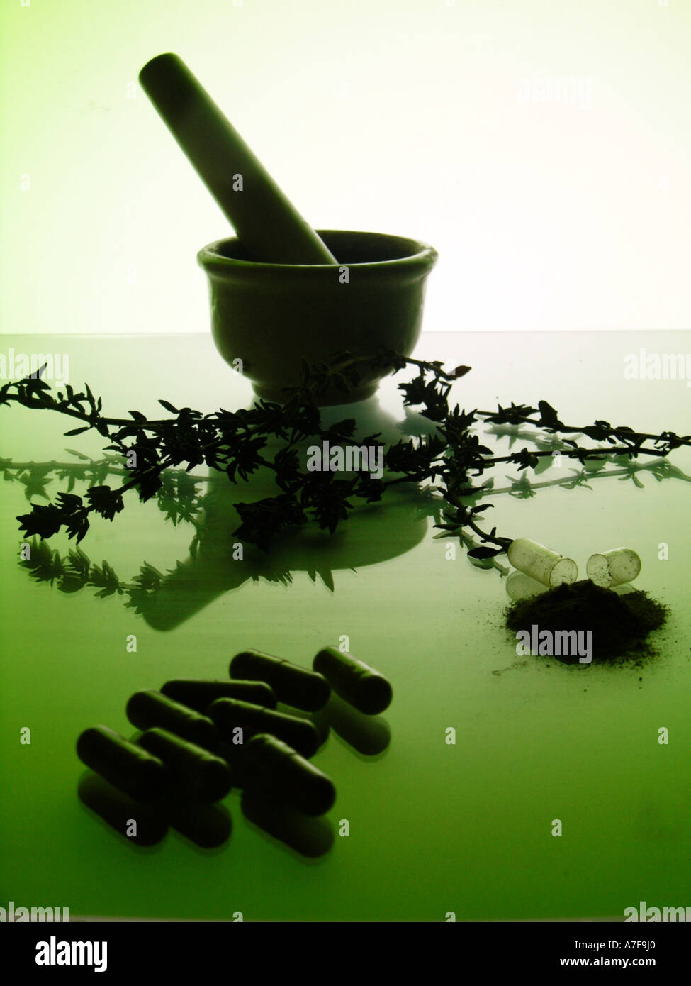 Backlit still life of mortar and pestle, medicine capsules and crushed ...