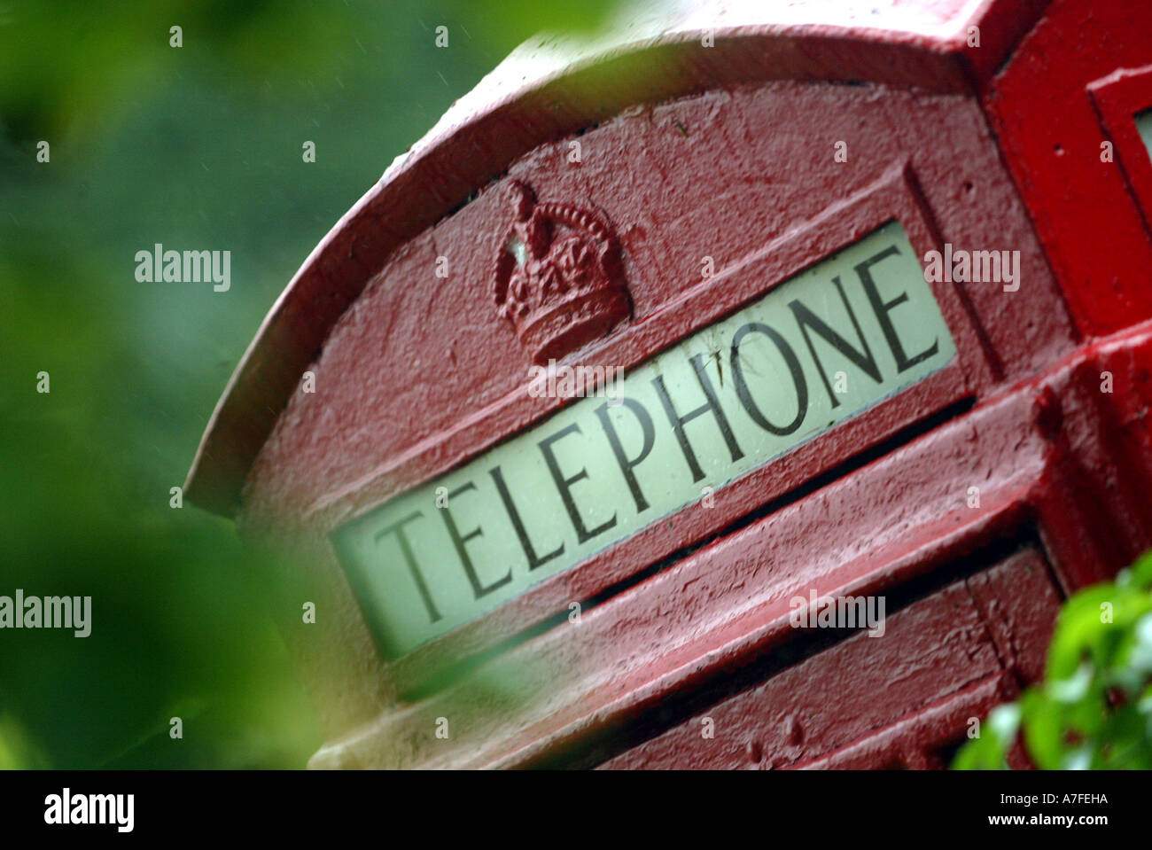 A traditional English Red Telephone Box is glimpsed through trees in a ...