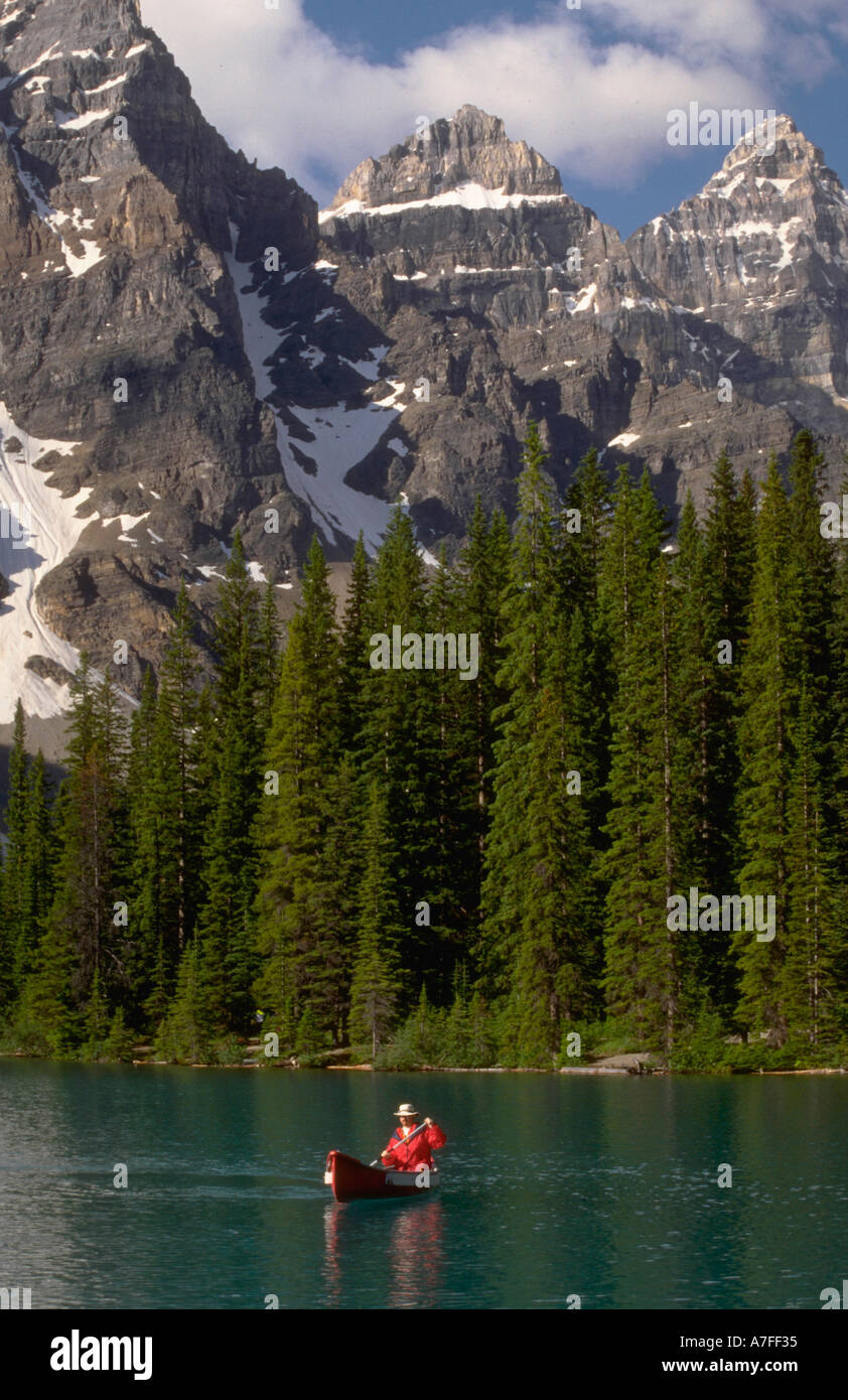 Man rowing in a canoe on Moraine Lake with snow covered mountains in ...