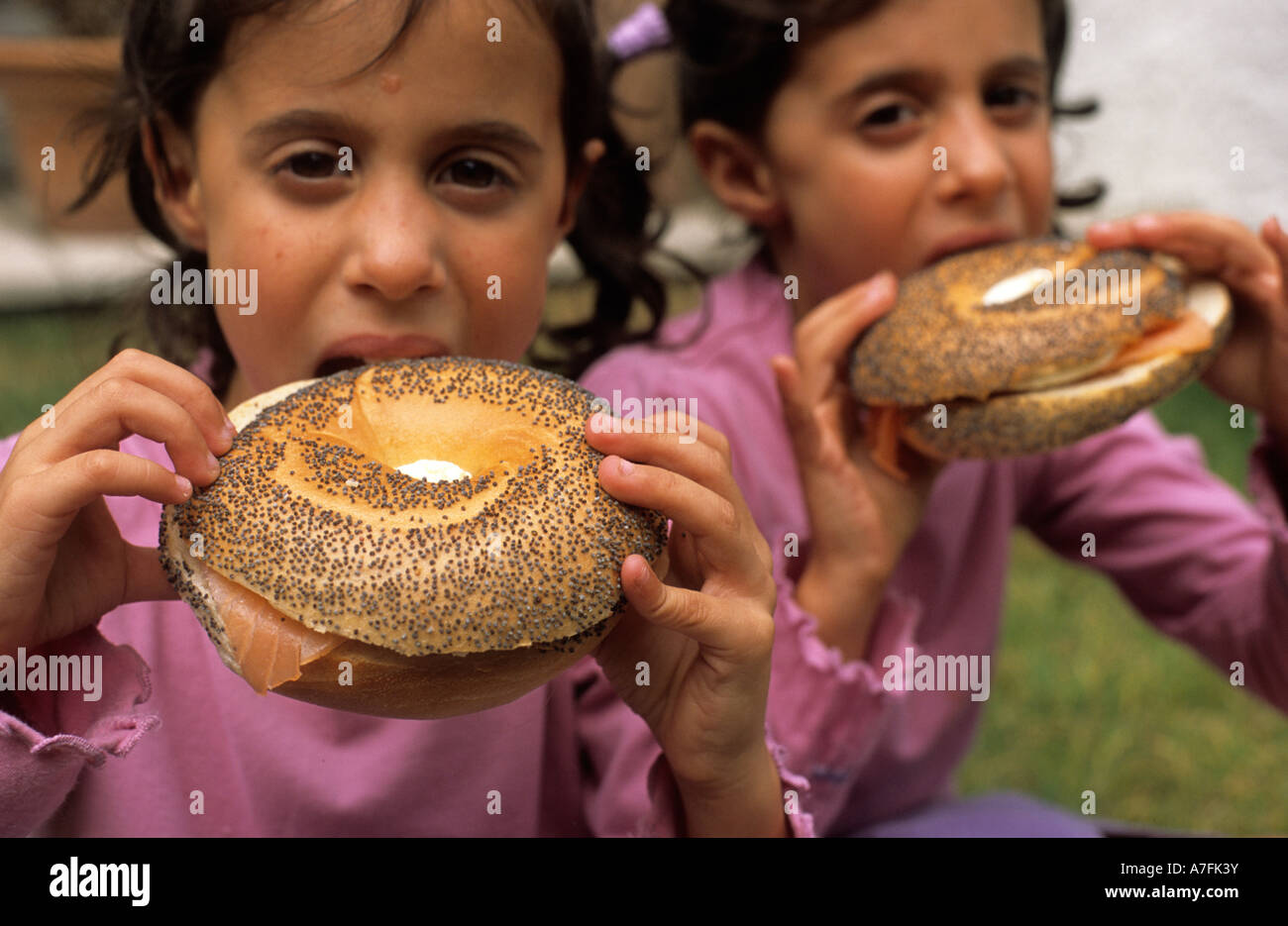 Young girl twins eating bagels Stock Photo - Alamy