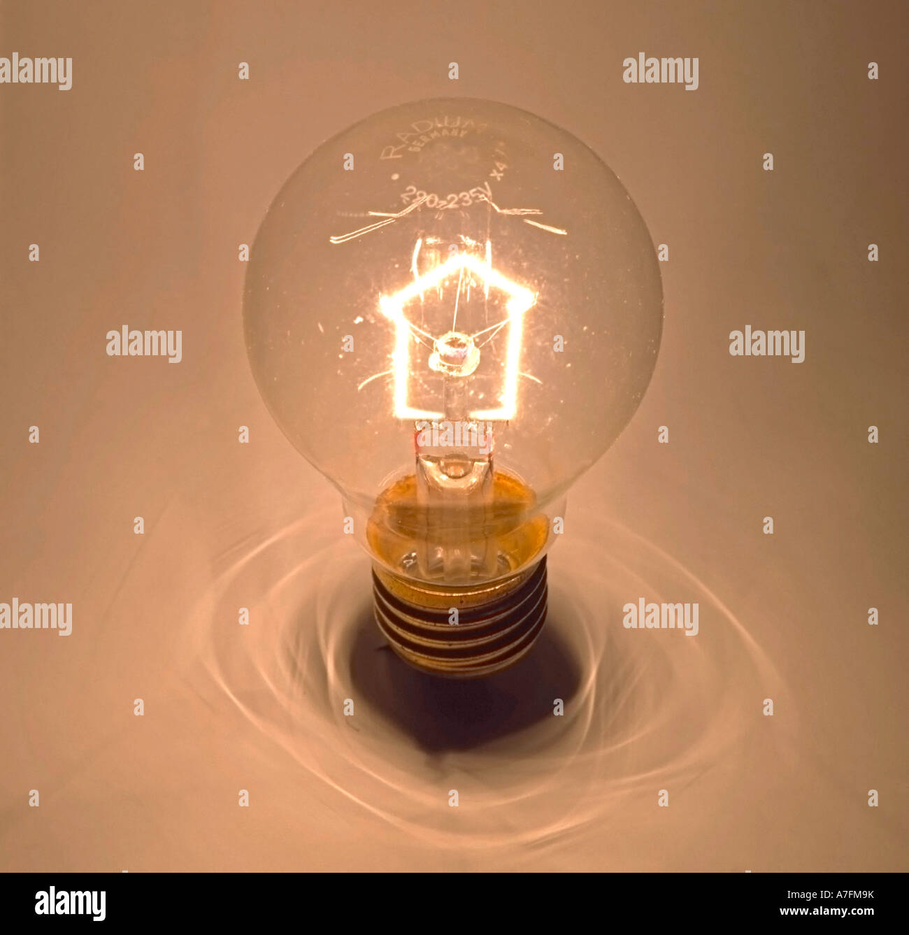 burning light bulb with aglowing luminecent filament in form of a house ...