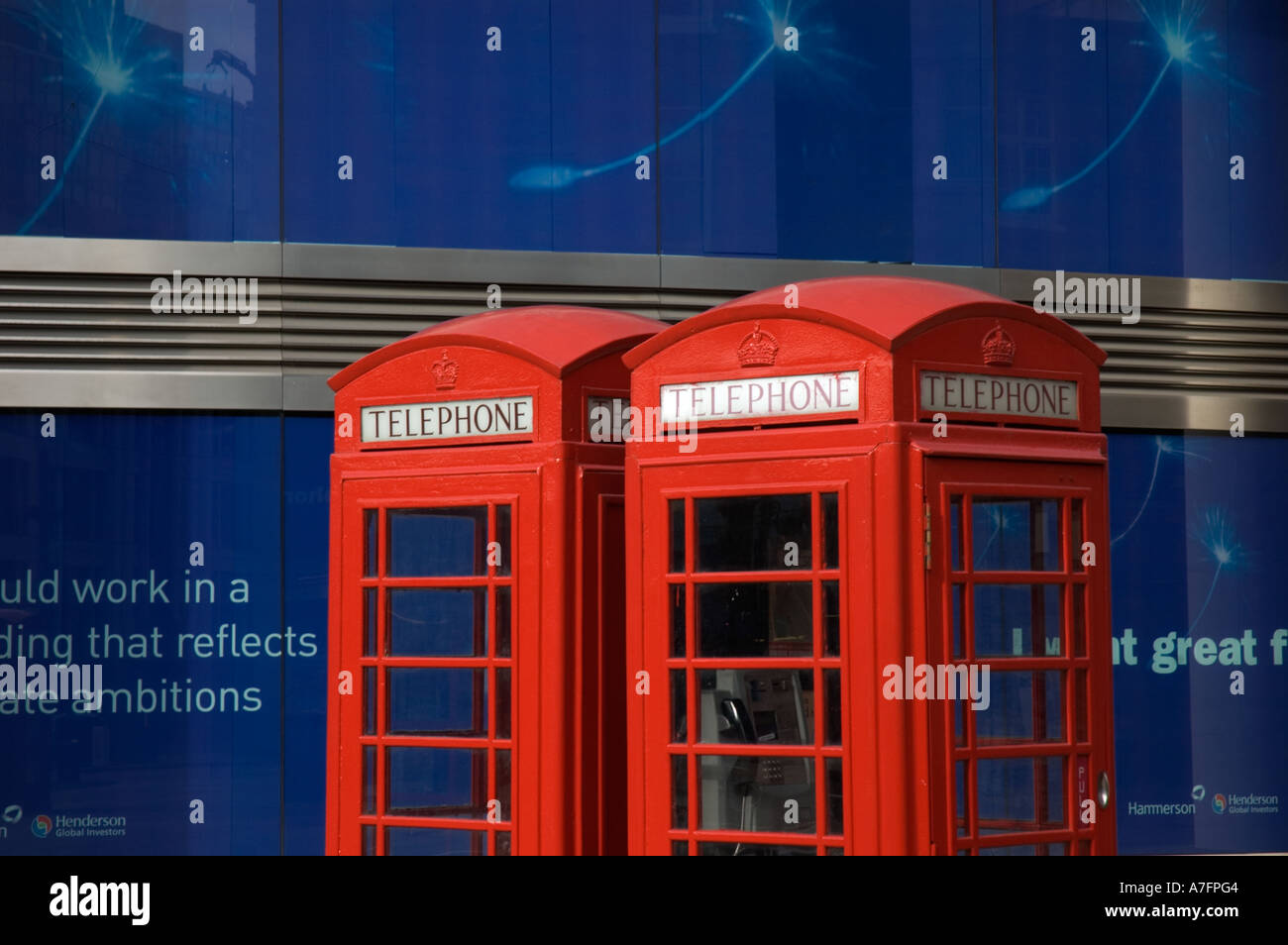 Two traditional red telephone boxes against blue advertisement on ...