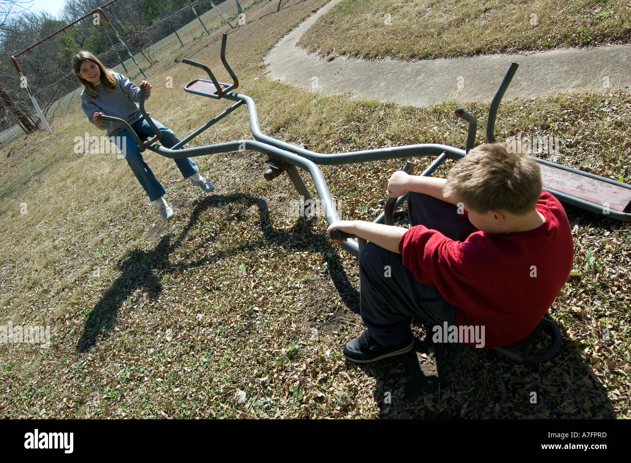 Boy and girl playing on old see saw in playground Stock Photo - Alamy