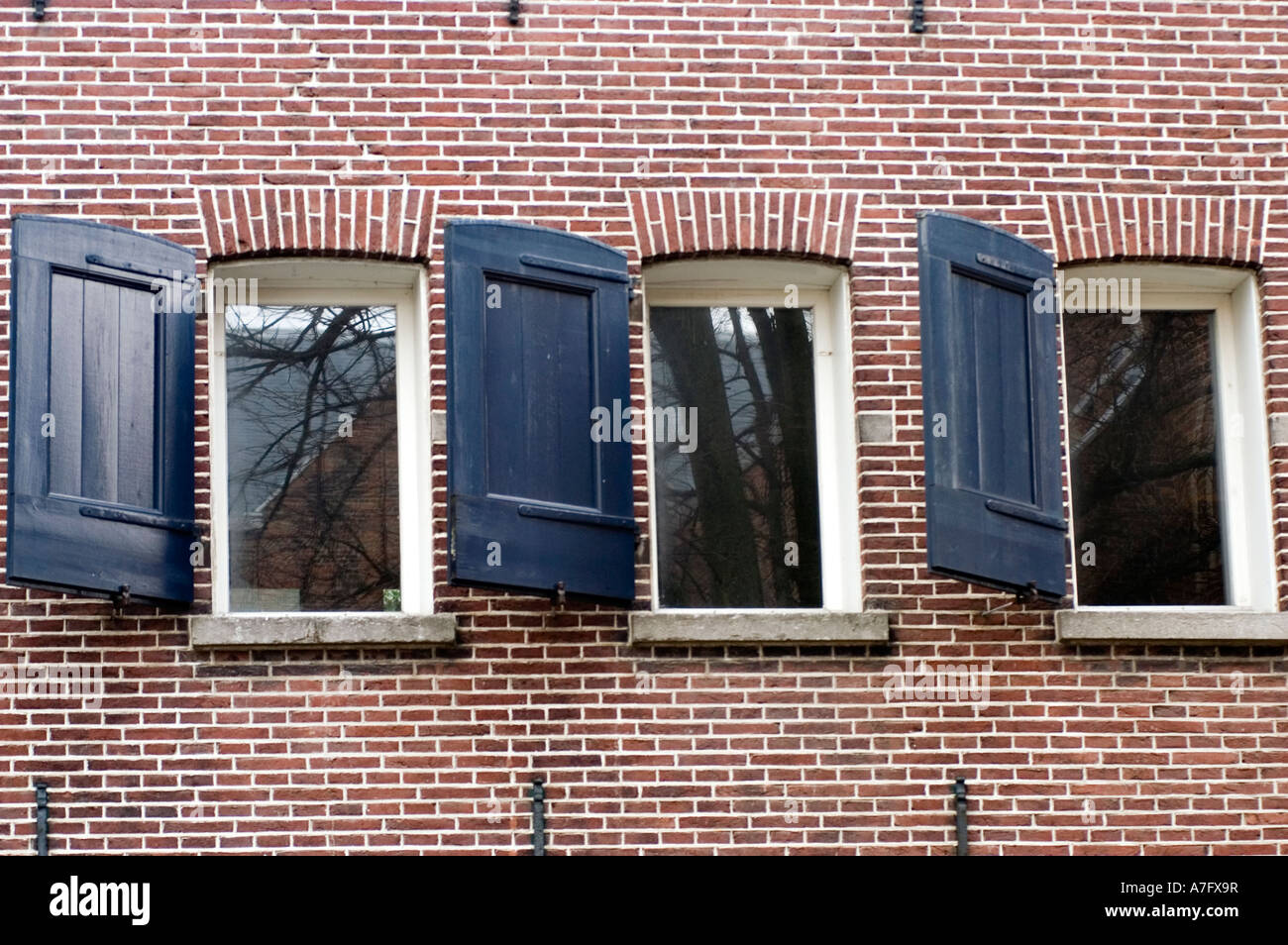 Three black shutter windows with dark red brick wall building facade ...