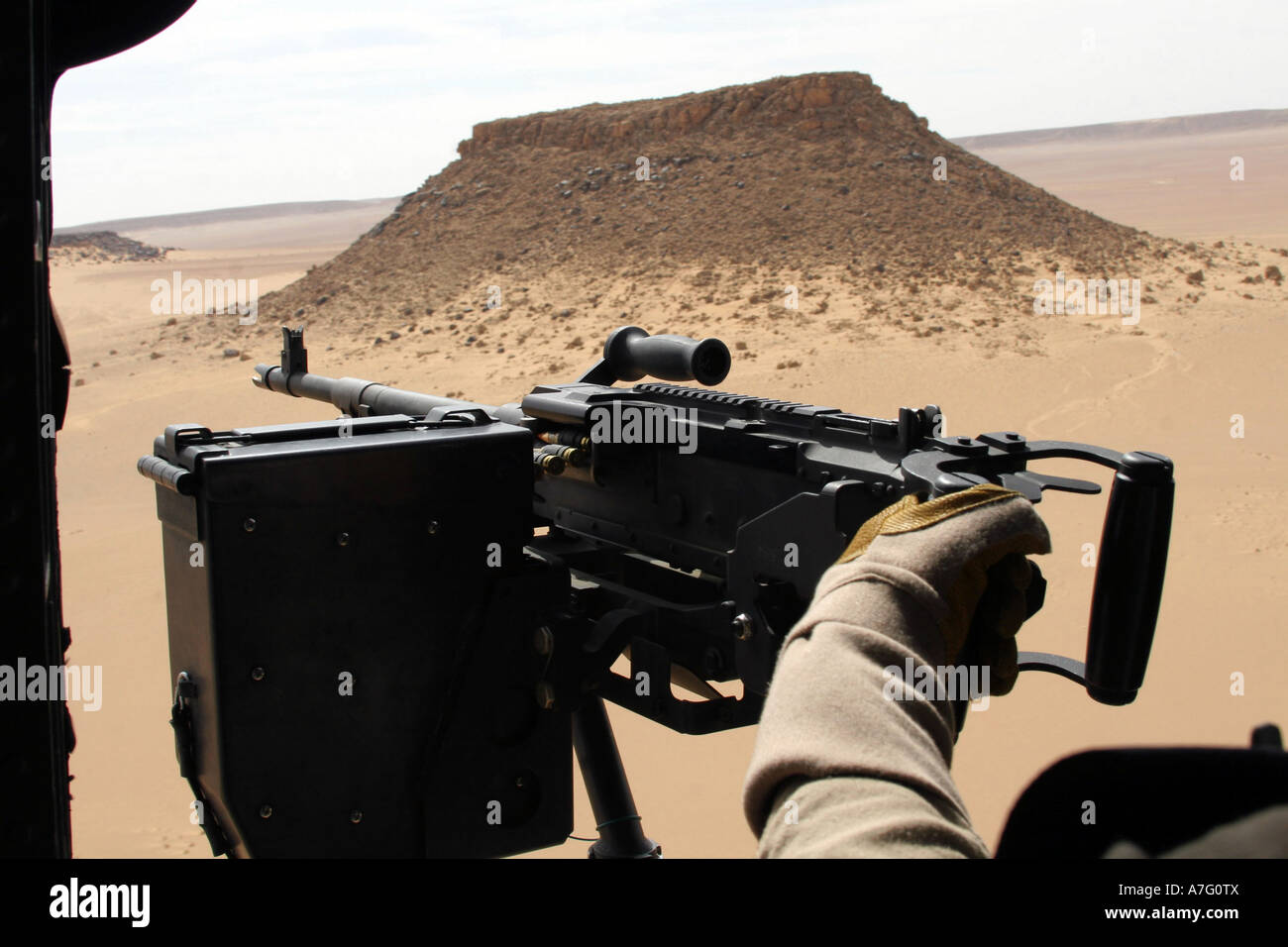 A UH-60 Blackhawk helicopter crew chief holds an M240G medium machine ...