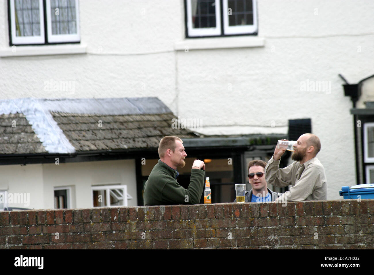 Three friends drinking outside a pub Stock Photo - Alamy