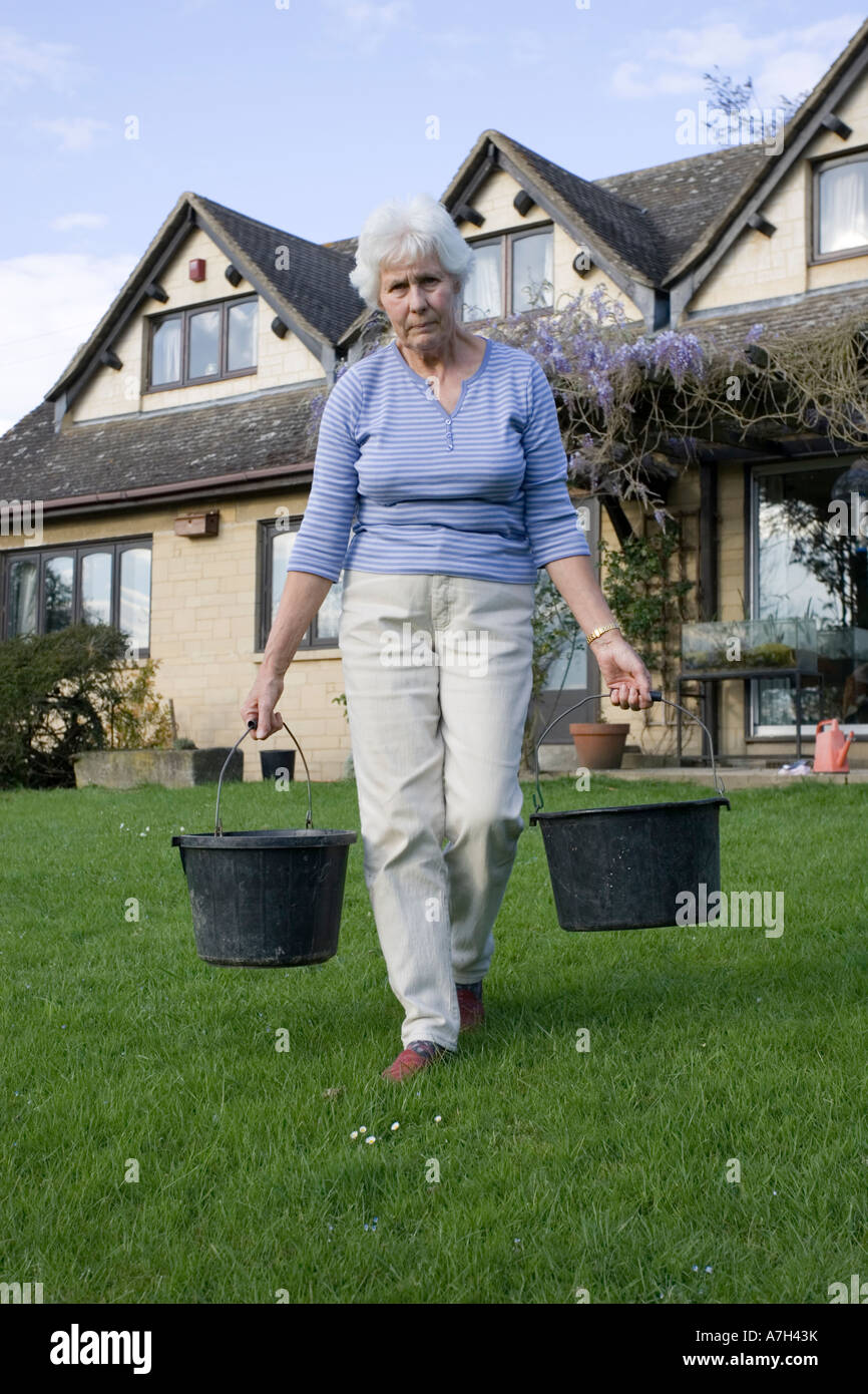 Woman carrying two black buckets across hi-res stock photography and ...