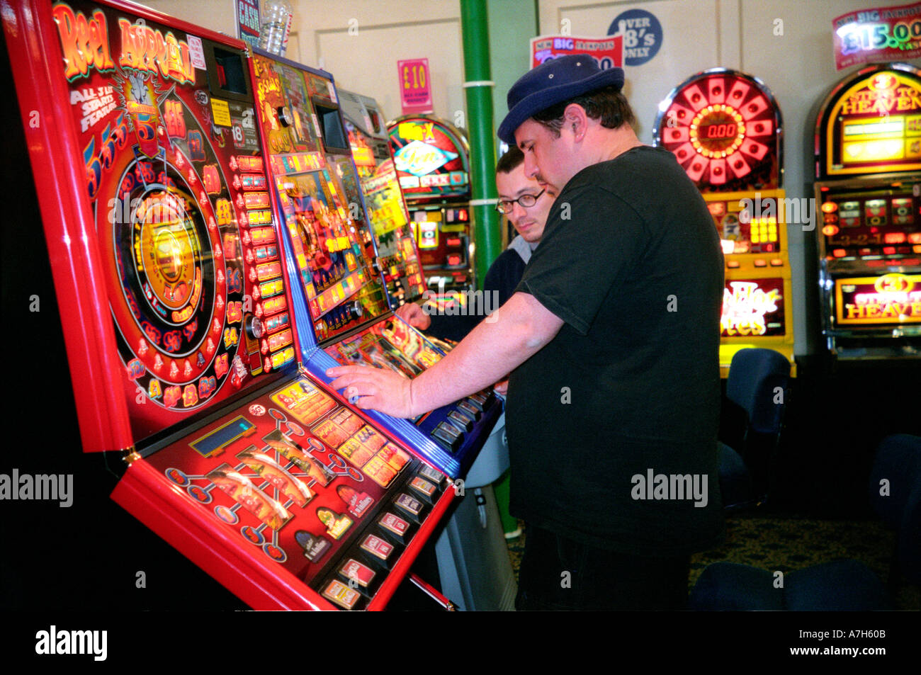 Man in games arcade playing on fruit machines Stock Photo - Alamy