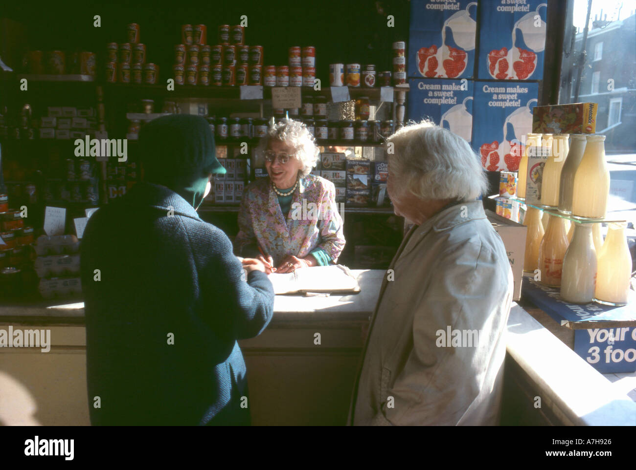 Shopkeeper talking to customers over the counter with milk bottles on ...
