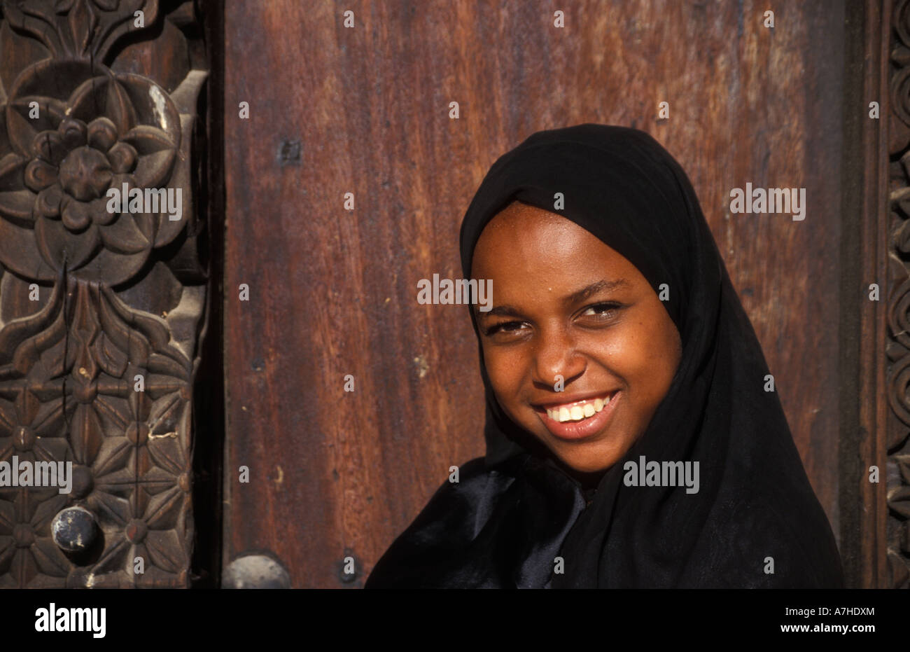 Swahili girl wearing traditional buibui standing at a Zanzibar door in ...