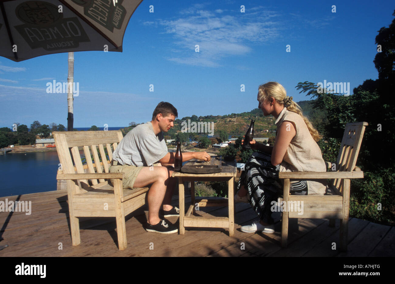 tourists sitting in a bar overlooking the lake, Nkhata Bay, Lake Malawi ...