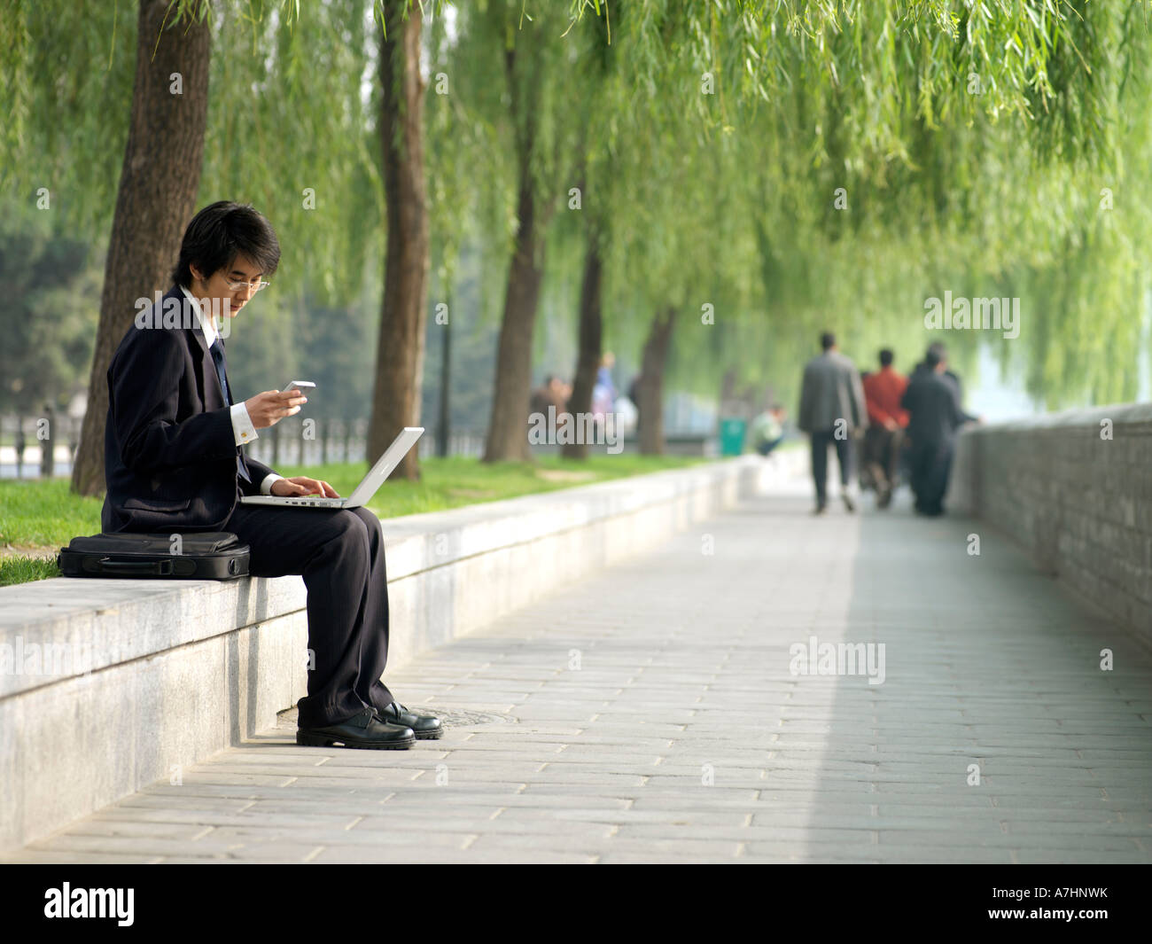 A young Chinese business man in a suit checking his email on his laptop ...